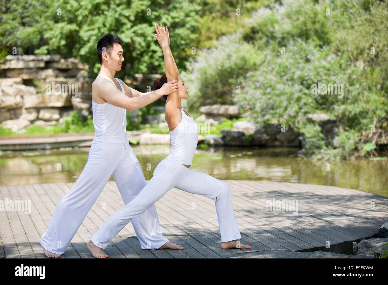 Yoga instructor helping woman with pose Stock Photo - Alamy