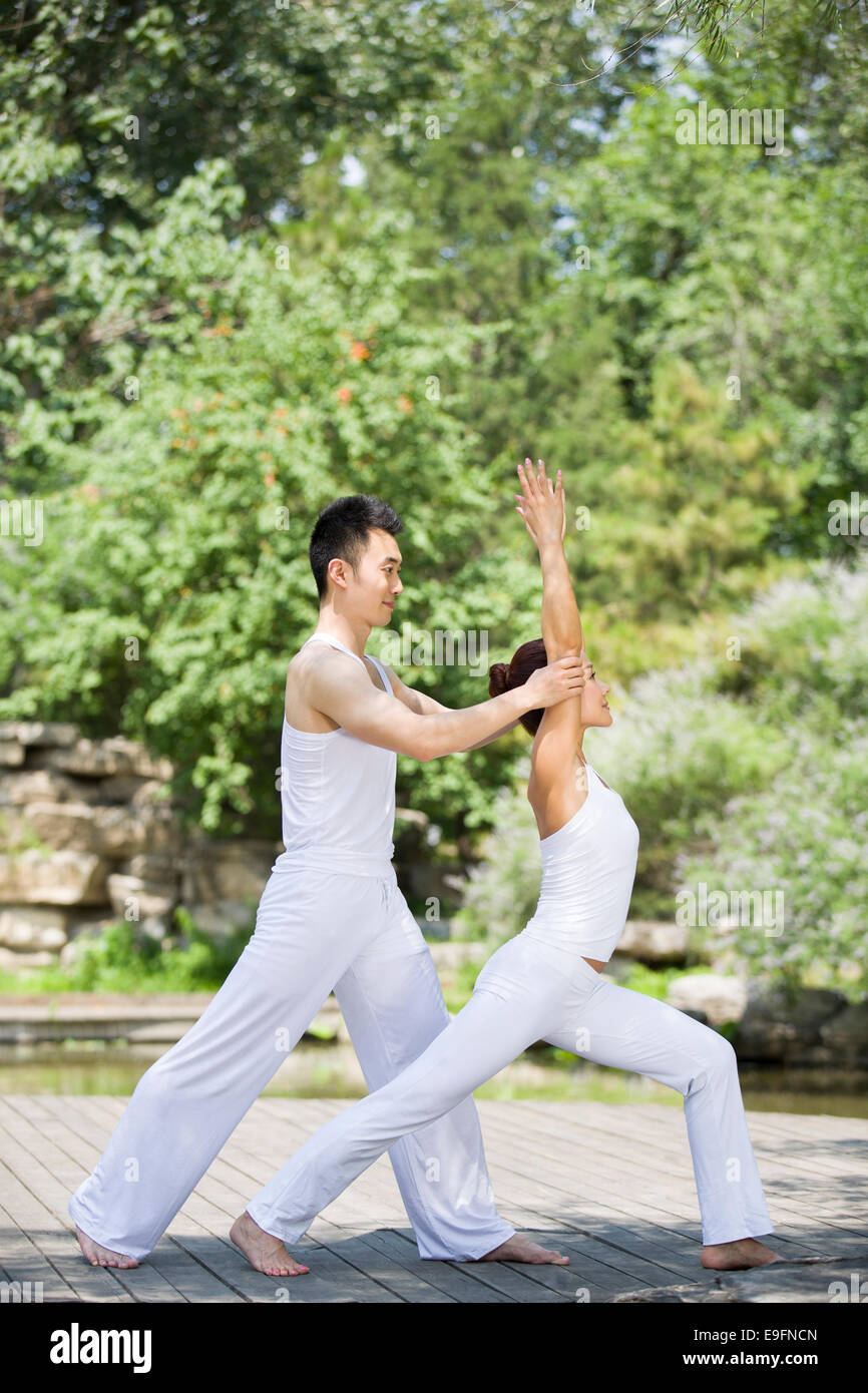 Yoga instructor helping woman with pose Stock Photo - Alamy