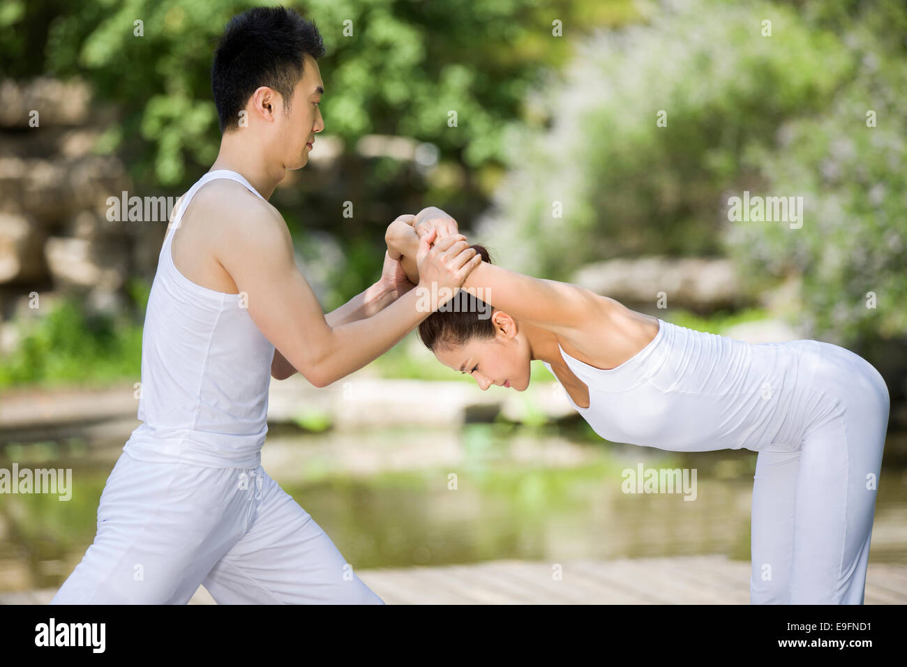 Yoga instructor helping woman with pose Stock Photo - Alamy