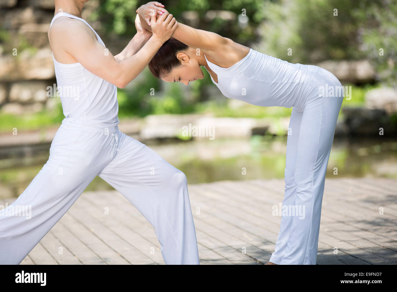 Yoga instructor helping woman with pose Stock Photo - Alamy