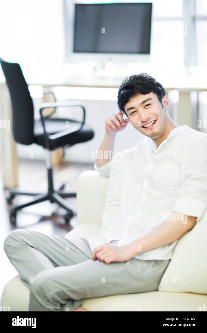 Portrait of young man sitting on sofa Stock Photo - Alamy