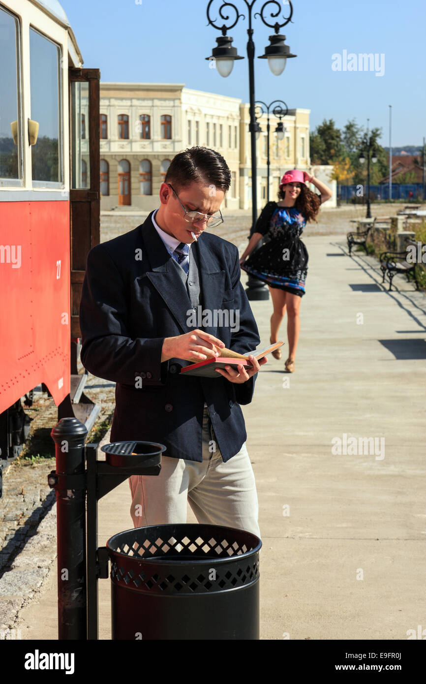 Romantic scene with man by the train reading book and retro woman ...