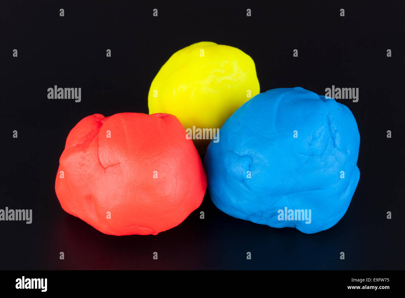 Colorful child's play clay (Red, Yellow, Blue) on black background ...