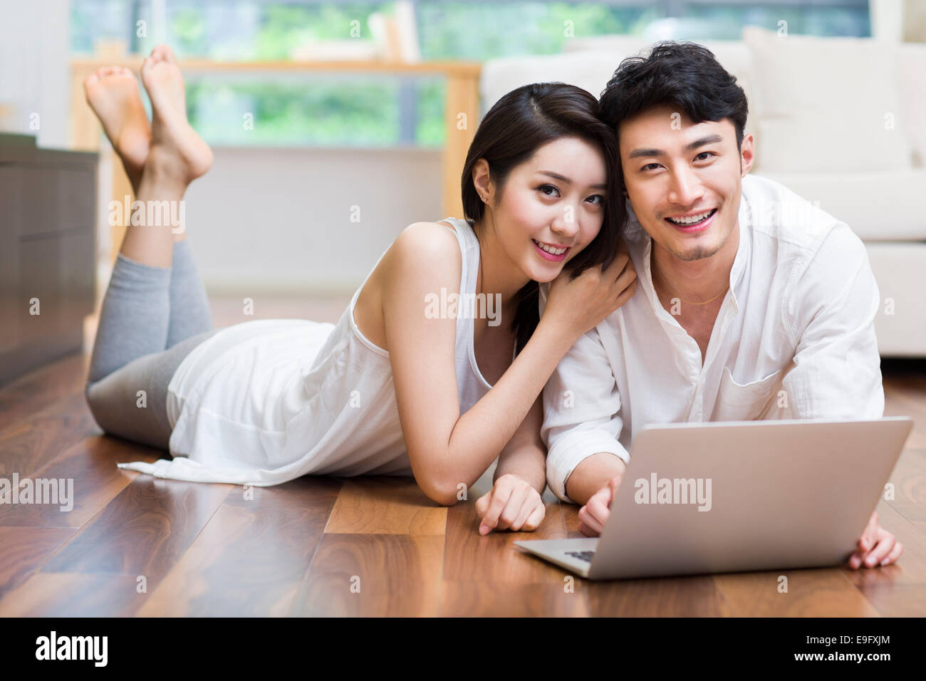 Young couple lying on floor using laptop Stock Photo - Alamy