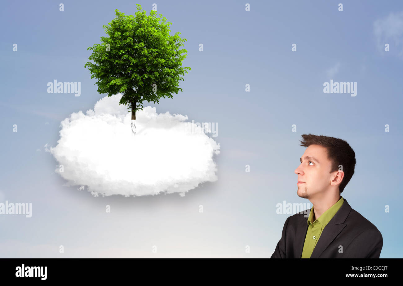 Young man pointing at a green tree on top of a white cloud Stock Photo ...