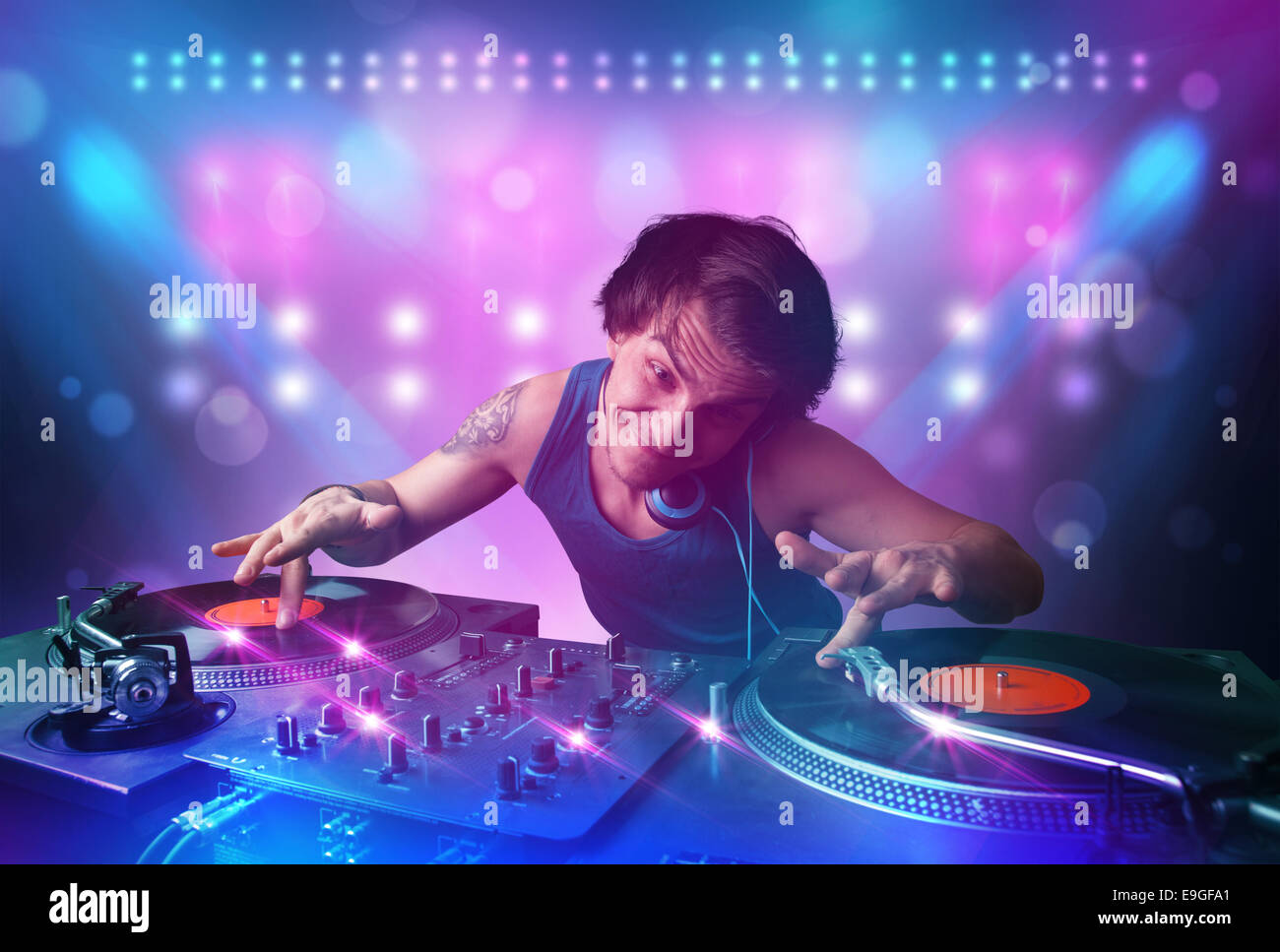 Disc jockey mixing music on turntables on stage with lights and ...