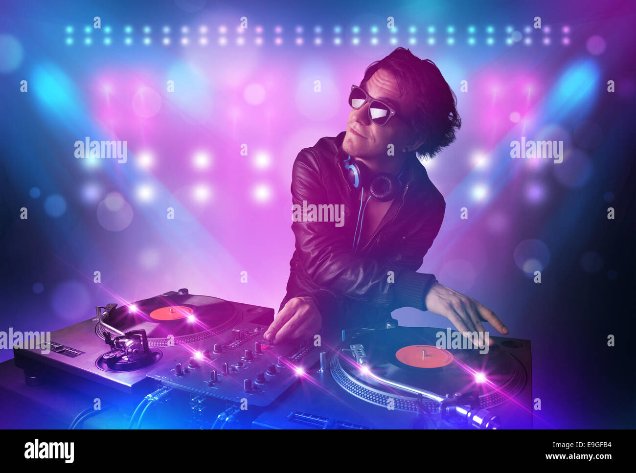 Disc jockey mixing music on turntables on stage with lights and ...
