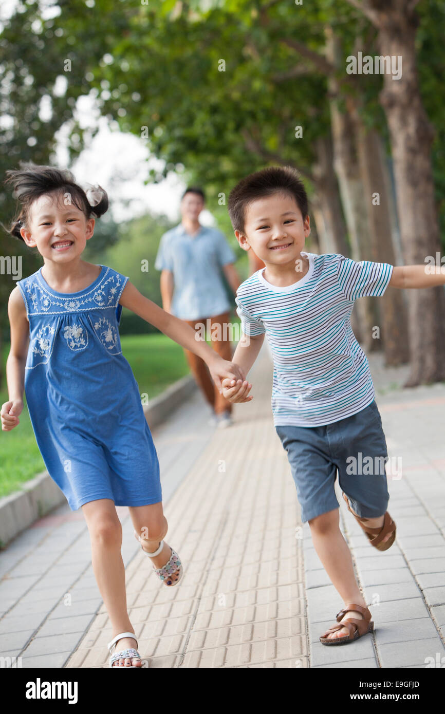 Happy brother and sister holding hands running Stock Photo - Alamy