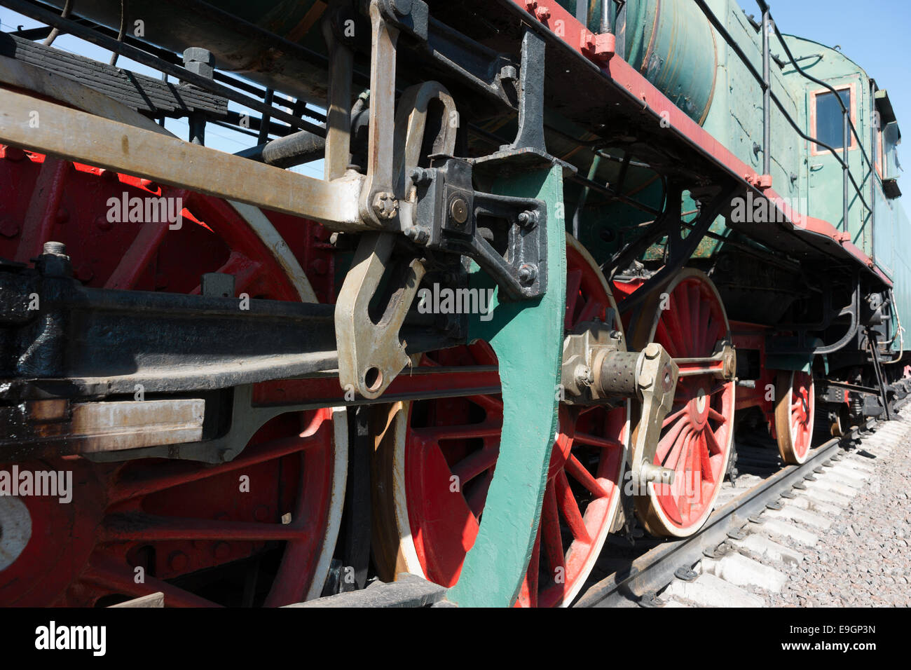 Partial view of a steam locomotive. Green metal boiler, red wheels ...