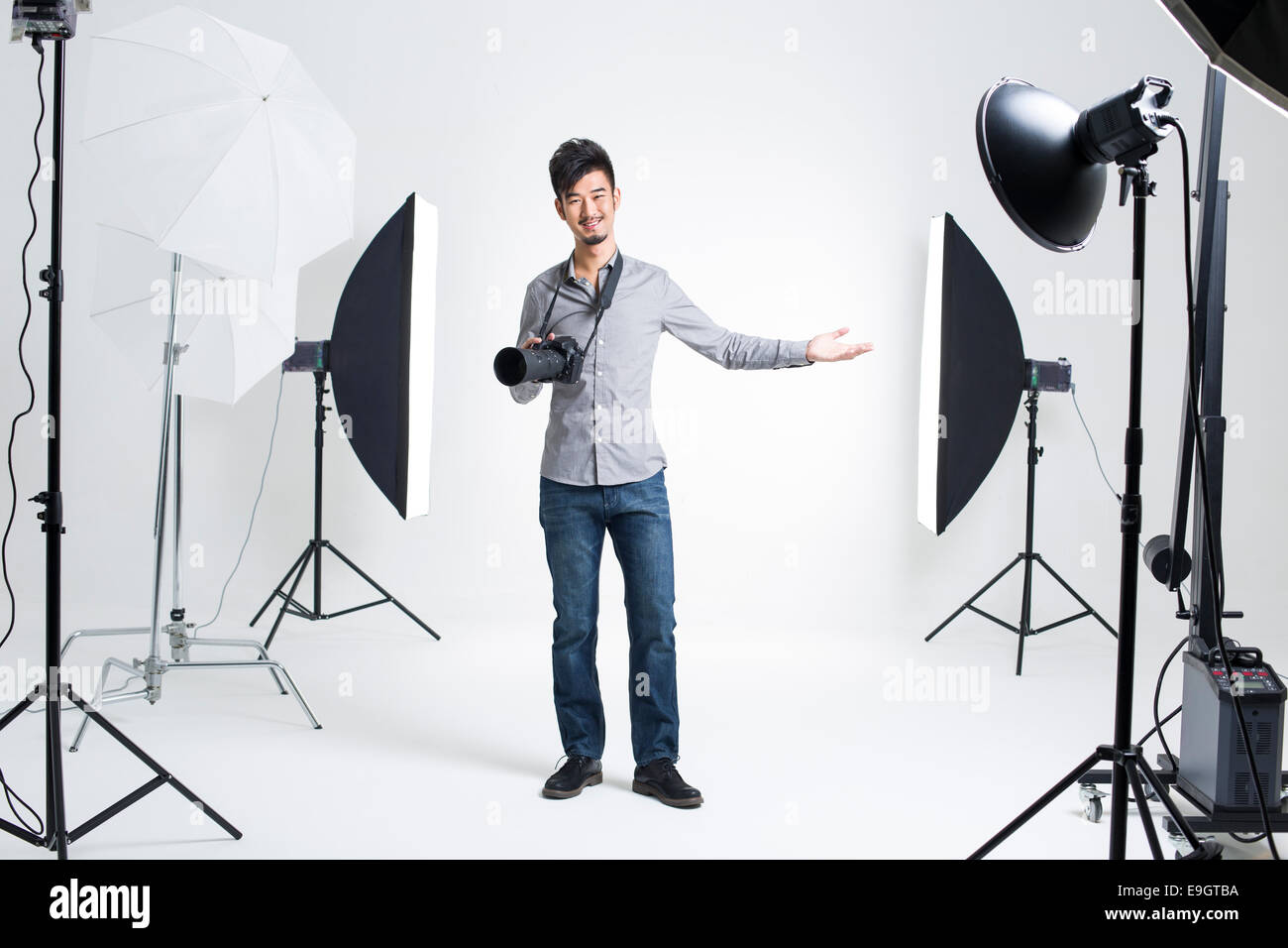 Photographer standing in studio with camera Stock Photo - Alamy