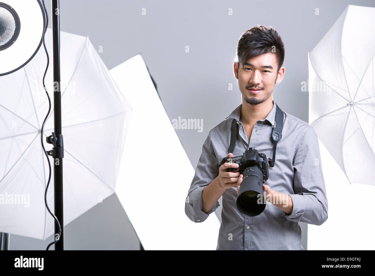Photographer standing in studio with camera Stock Photo - Alamy