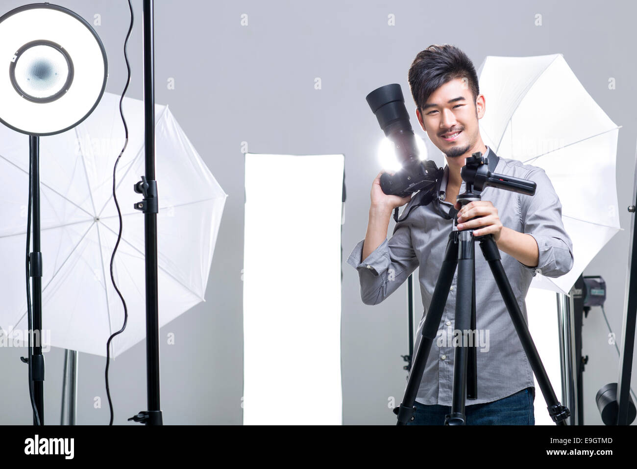 Photographer standing in studio with camera Stock Photo - Alamy