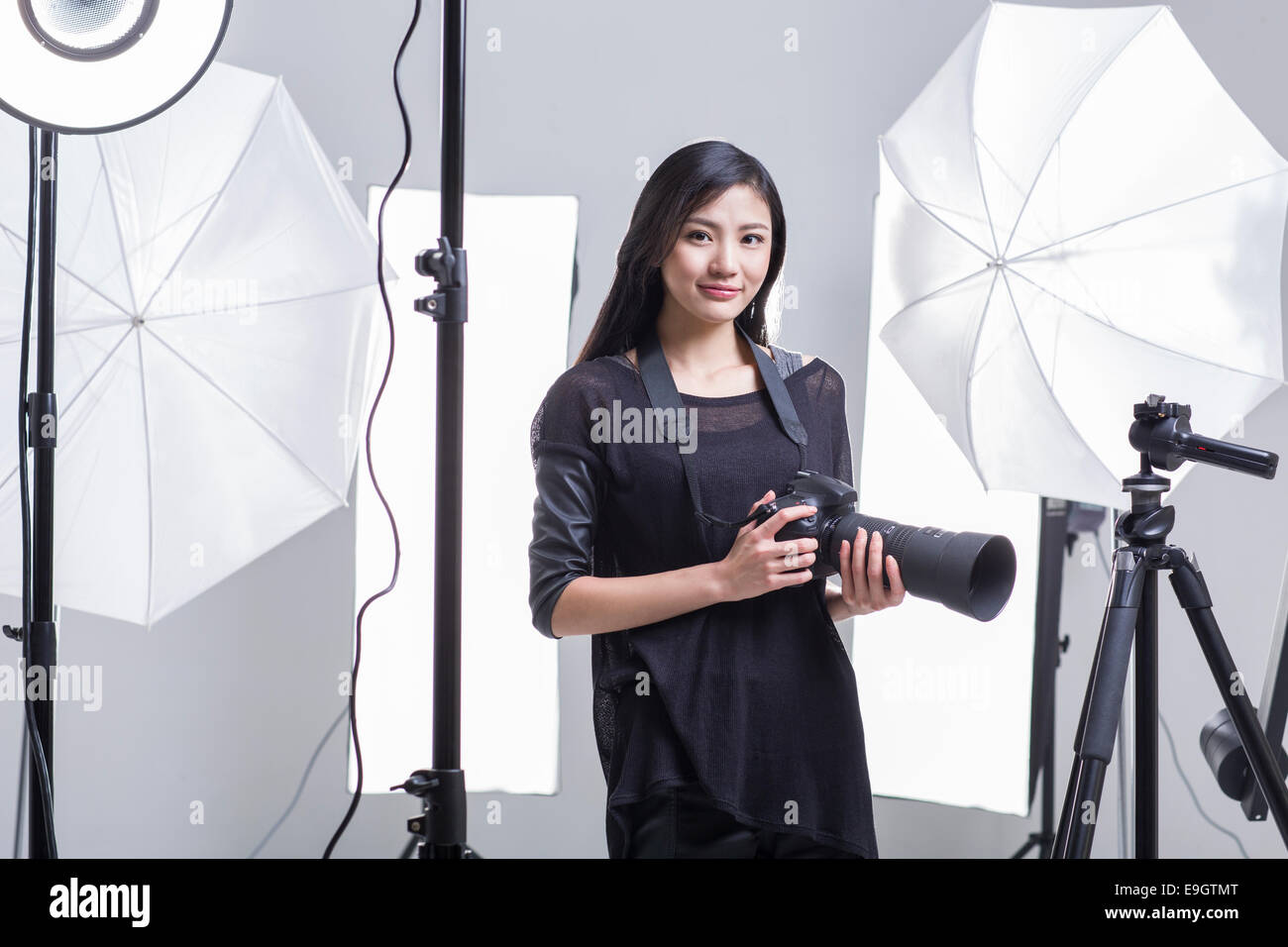 Photographer standing in studio with camera Stock Photo - Alamy