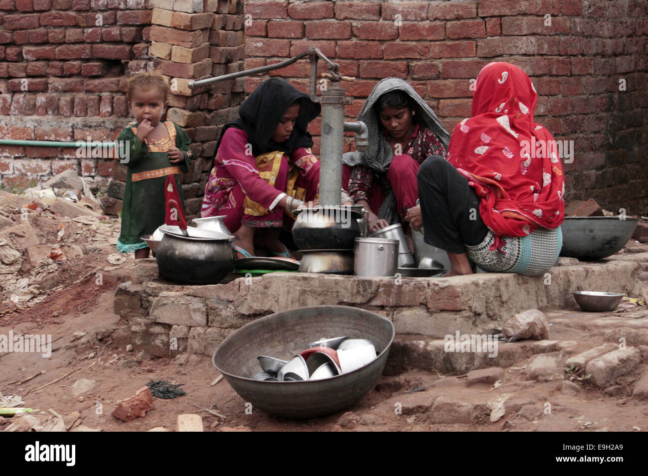 Lahore. 28th Oct, 2014. Pakistani girls wash vessels outside their ...