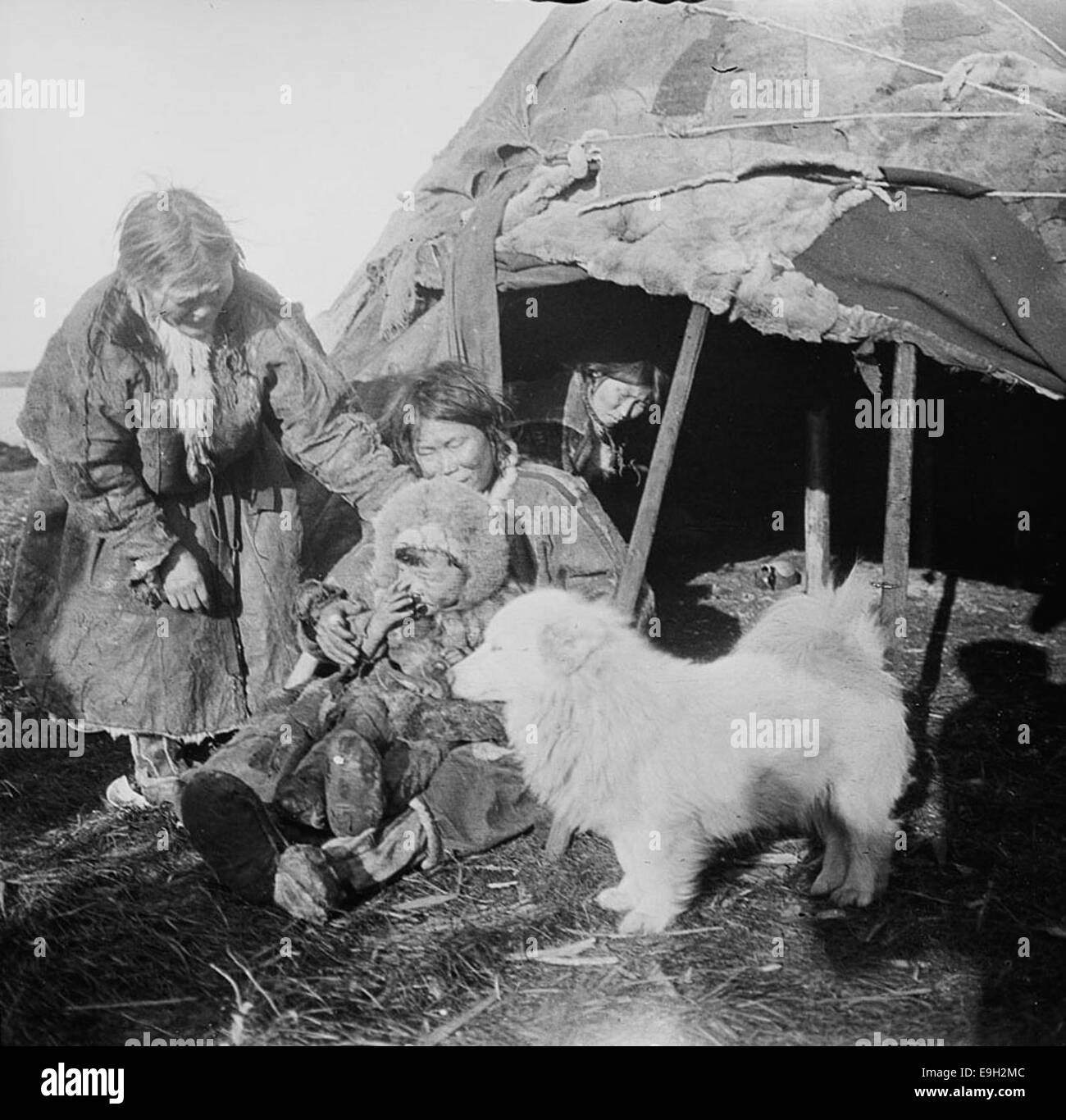 A photograph of a Nenets woman with a child and a dog in front of their ...