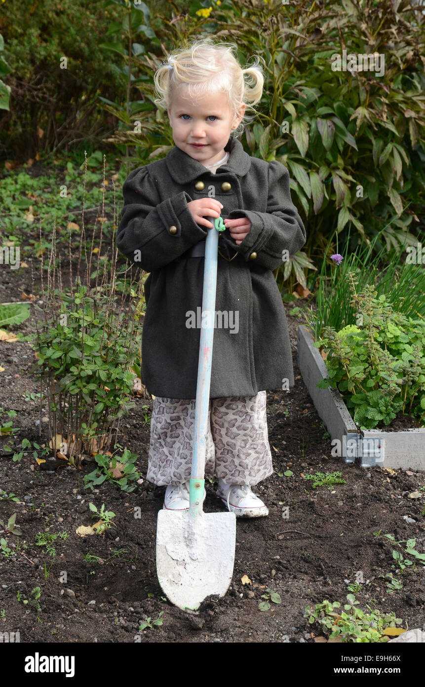 Girl, 2 years, with a spade in the garden, Ystad, Scania, Sweden Stock ...