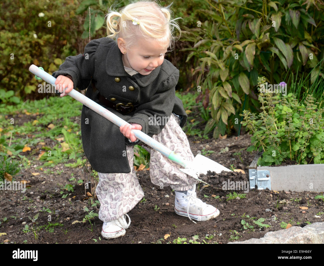 Girl, 2 years, working with a spade in the garden, Ystad, Scania ...