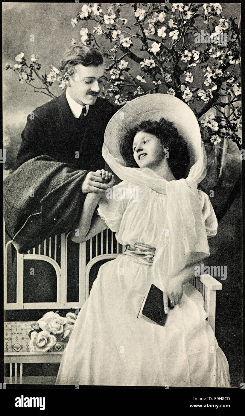 A staged photograph of a romantic couple sitting on a bench ...