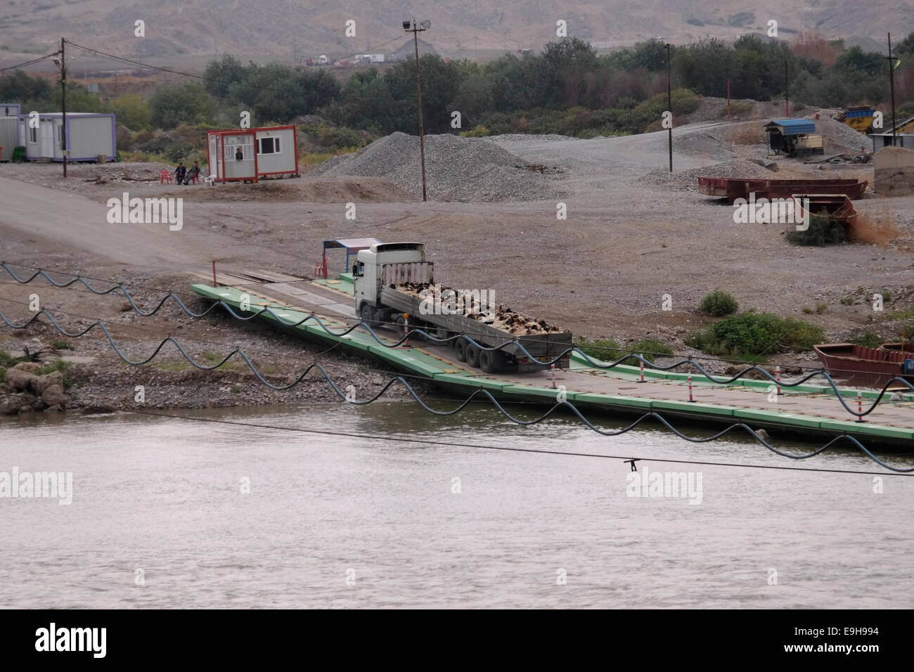 A truck loaded with sheep and lambs crossing a pontoon bridge over the ...