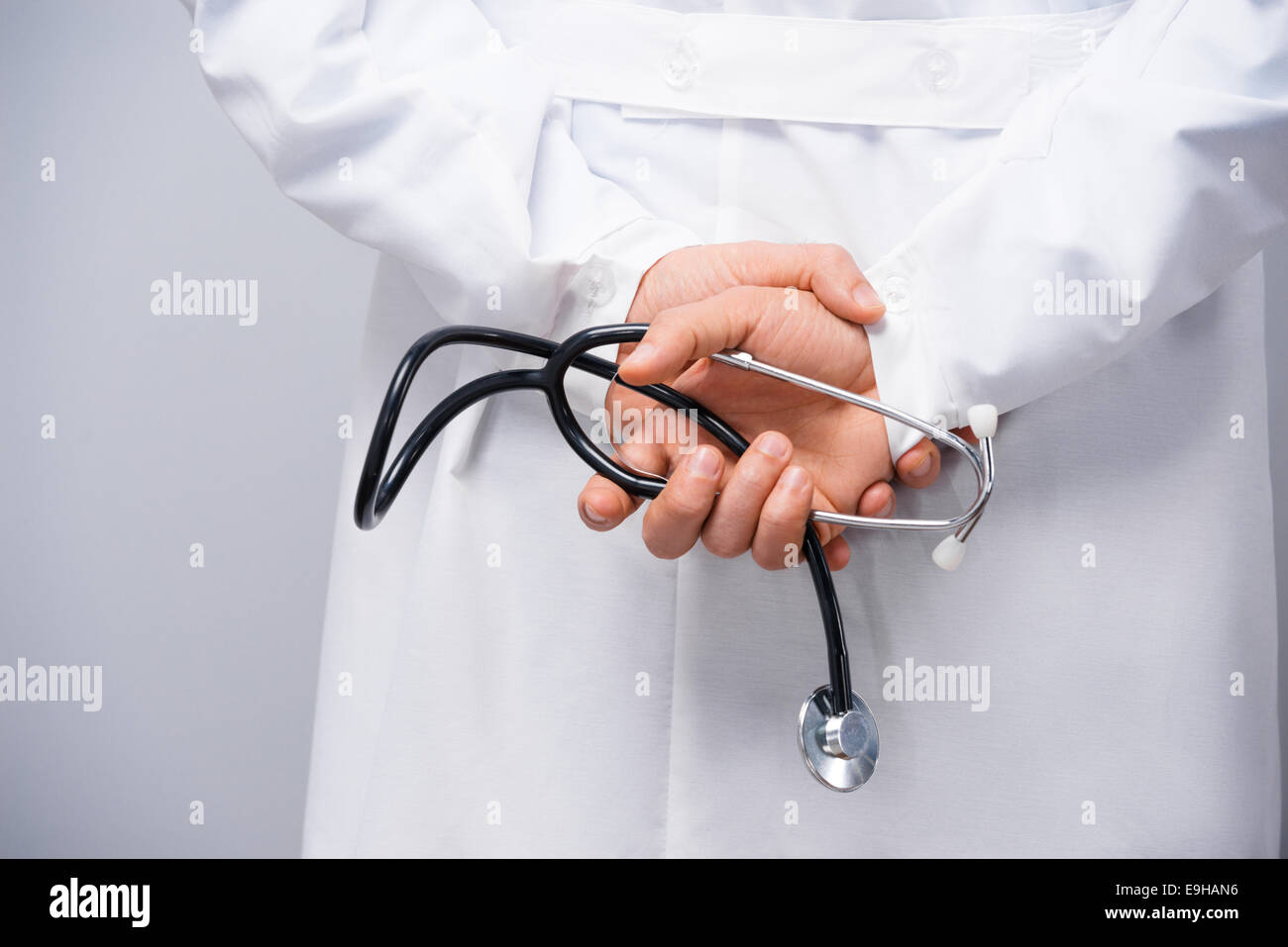 Doctor holding stethoscope behind his back on grey background Stock ...