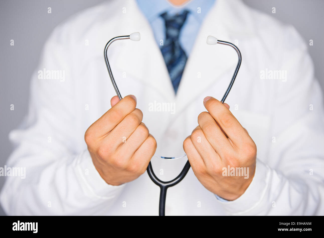 Doctor showing stethoscope to the camera isolated on grey background ...