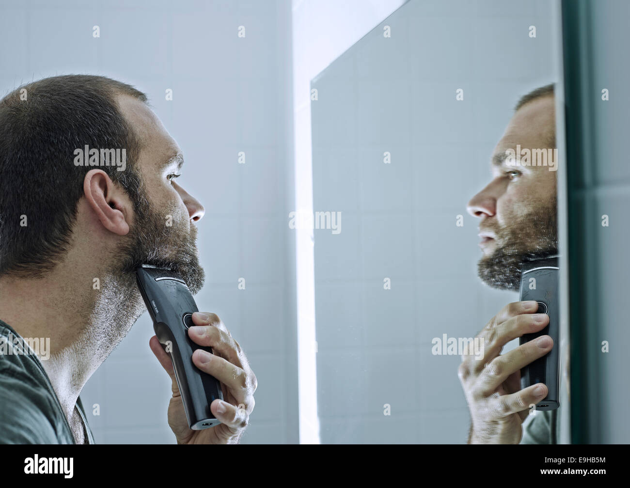 Man shaving his beard in front of a mirror Stock Photo - Alamy