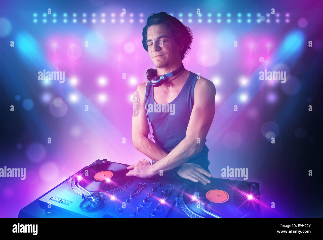 Disc jockey mixing music on turntables on stage with lights and ...