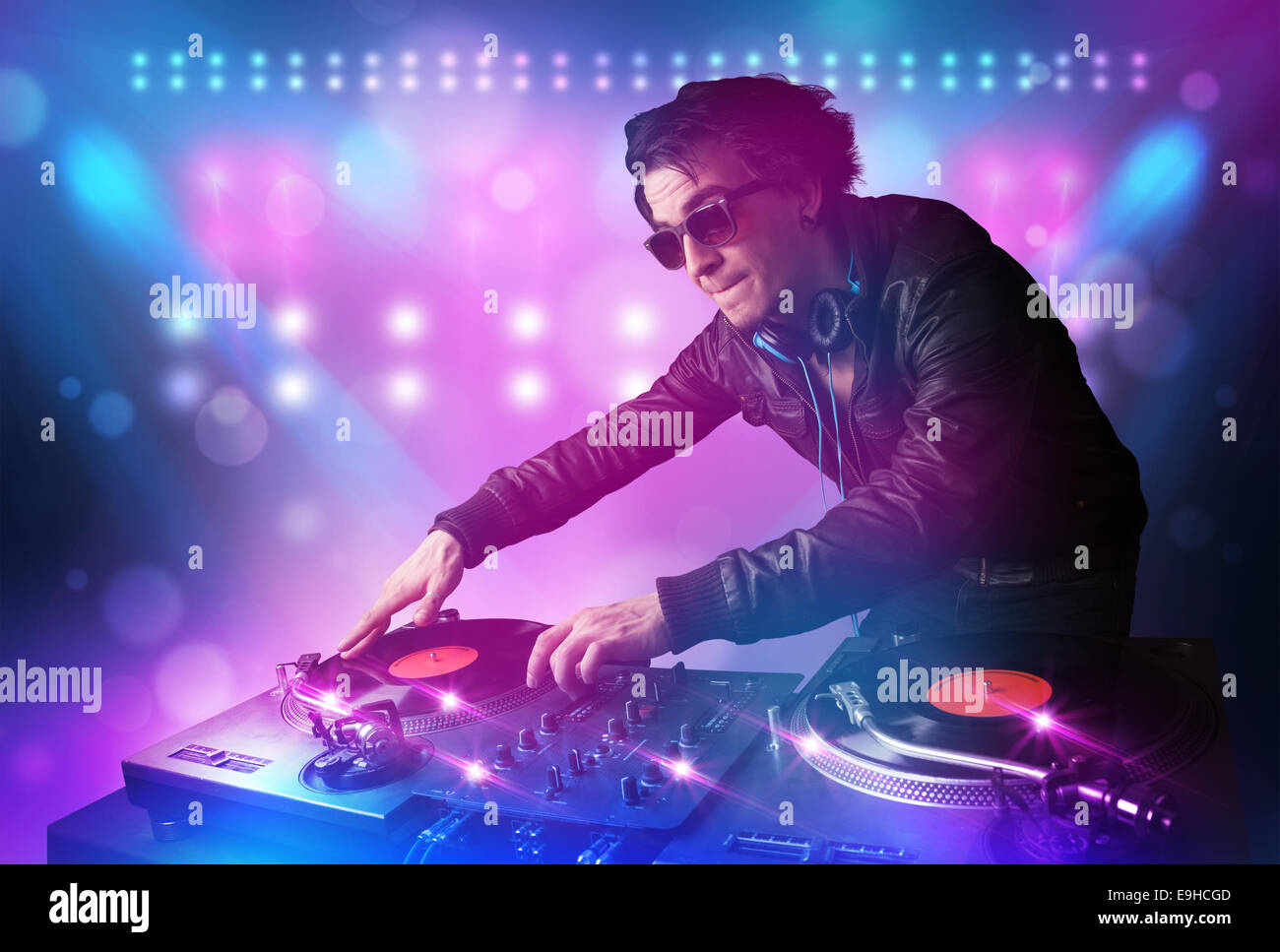 Disc jockey mixing music on turntables on stage with lights and ...