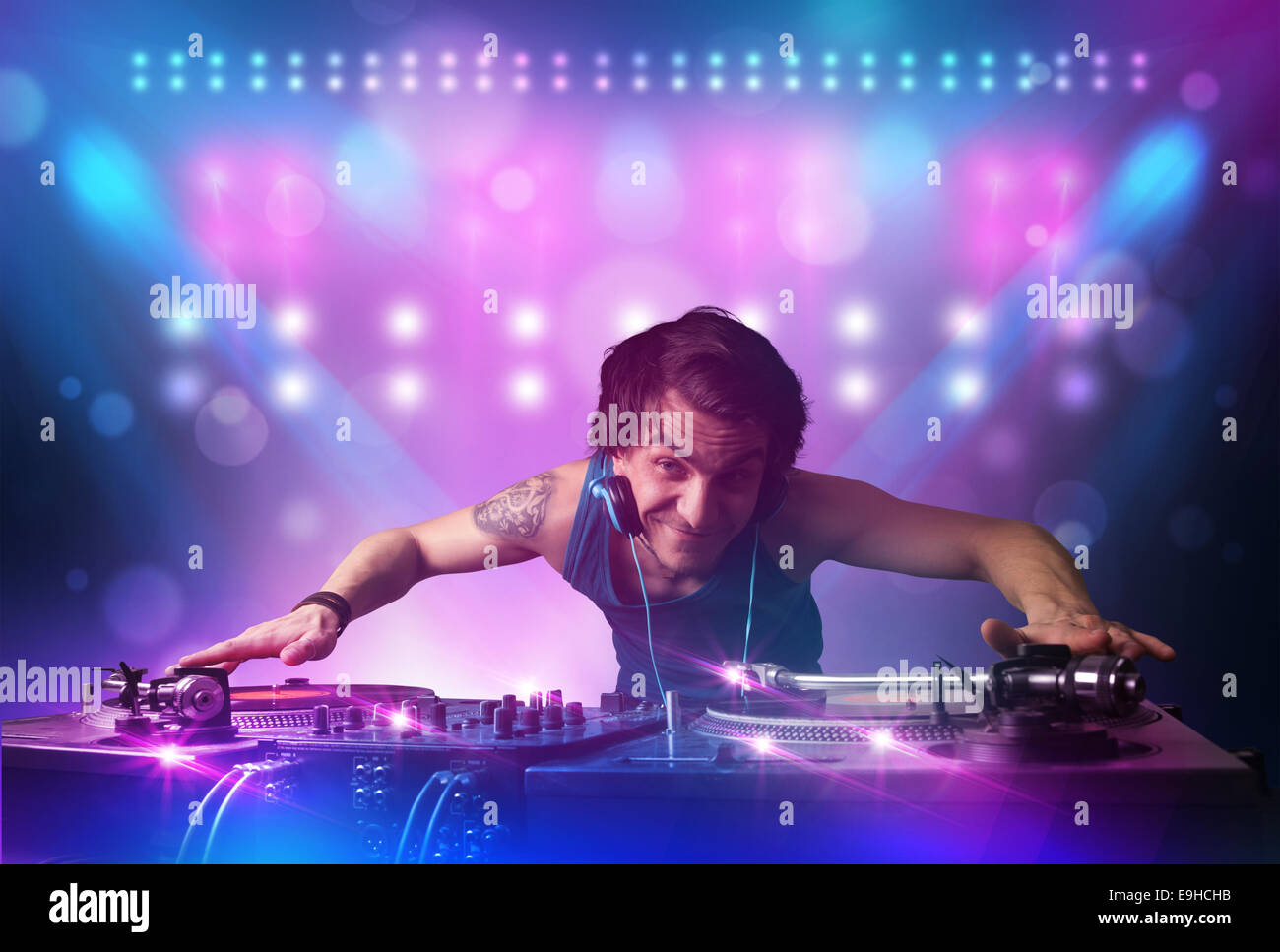 Disc jockey mixing music on turntables on stage with lights and ...