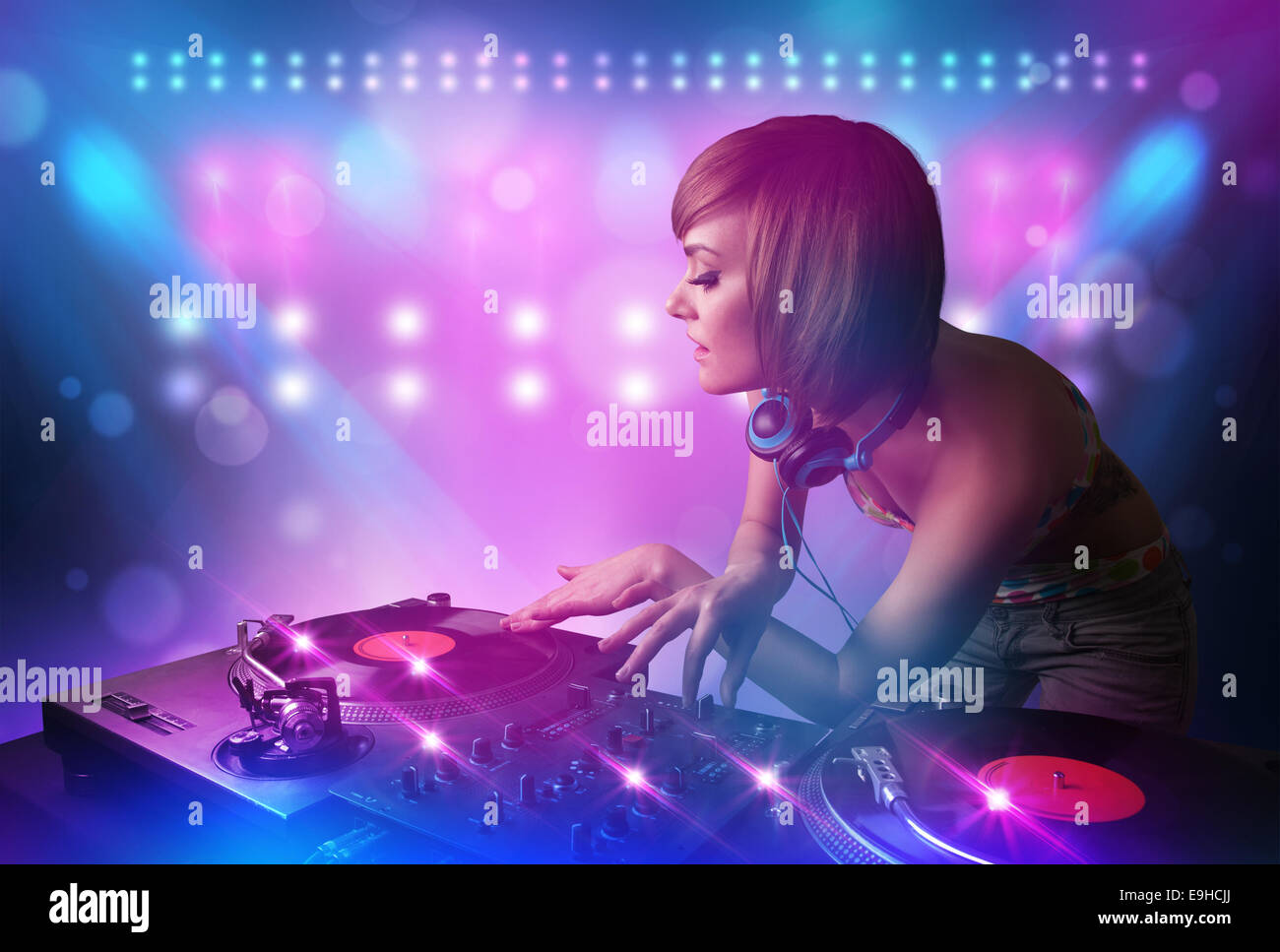 Disc jockey mixing music on turntables on stage with lights and ...