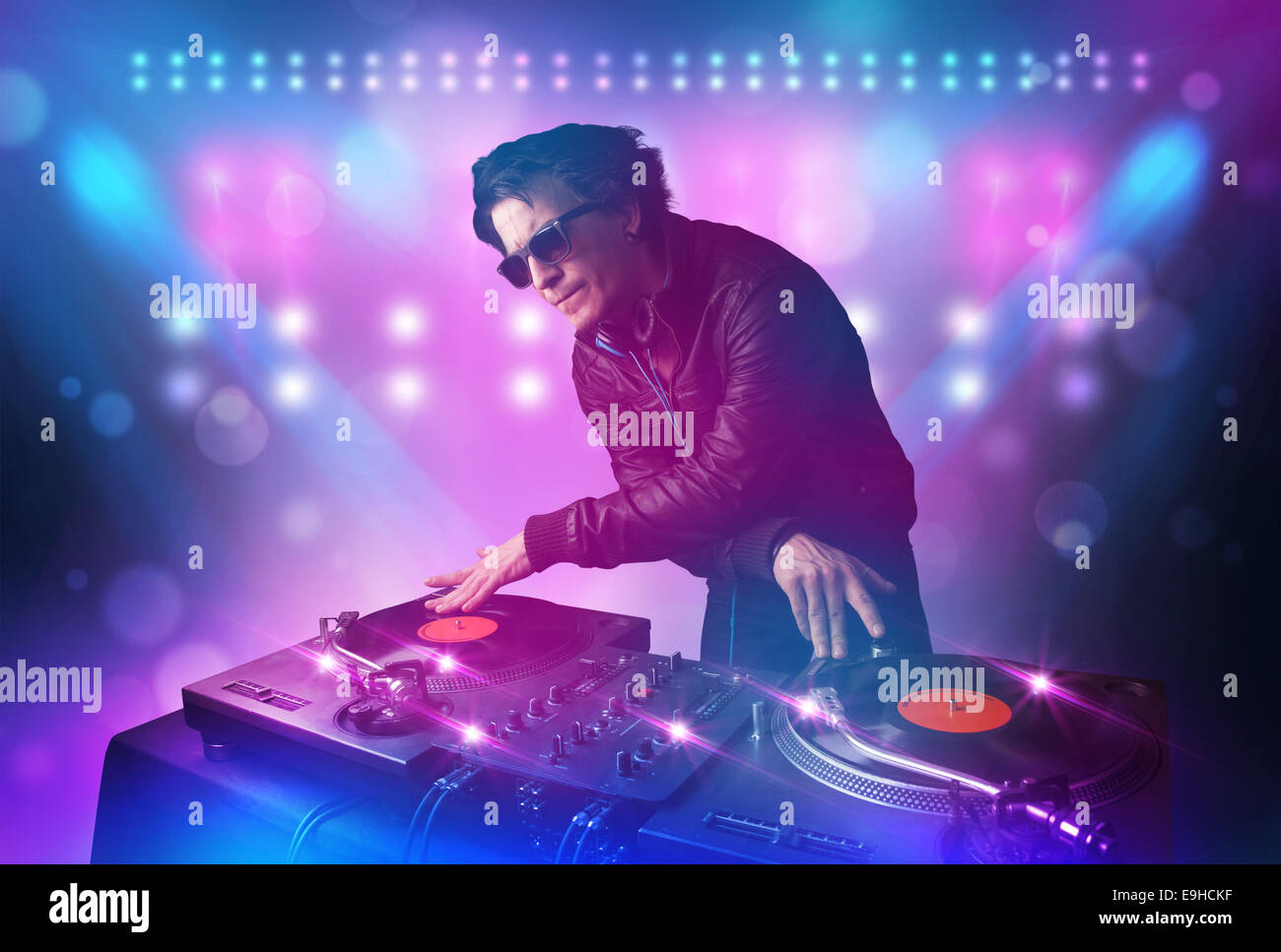 Disc jockey mixing music on turntables on stage with lights and ...