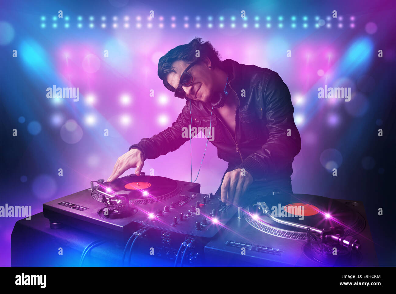 Disc jockey mixing music on turntables on stage with lights and ...