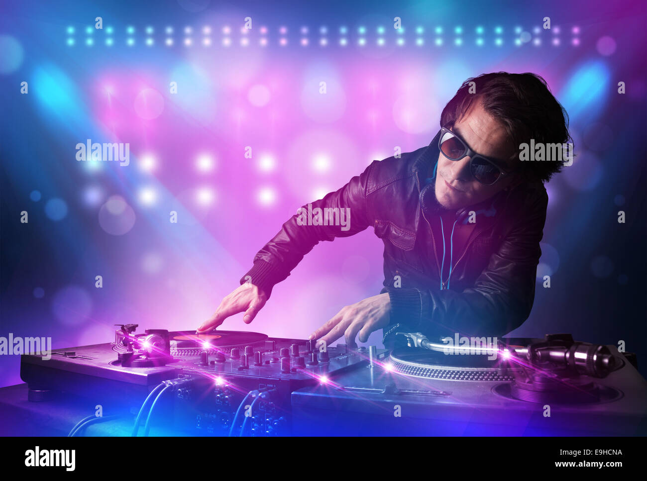 Disc jockey mixing music on turntables on stage with lights and ...