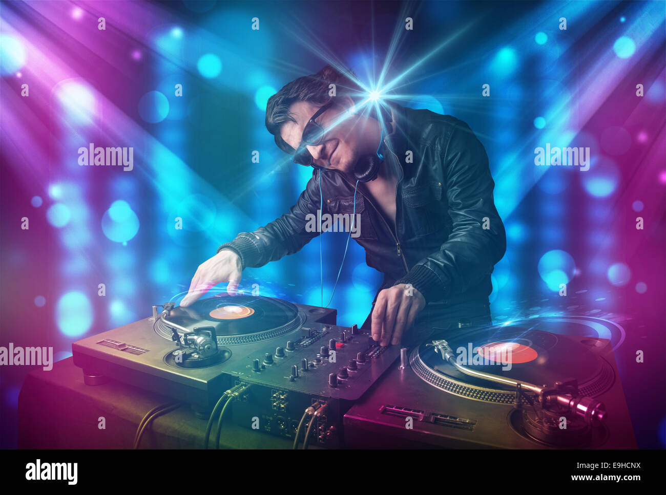 Dj mixing music in a club with blue and purple lights Stock Photo - Alamy