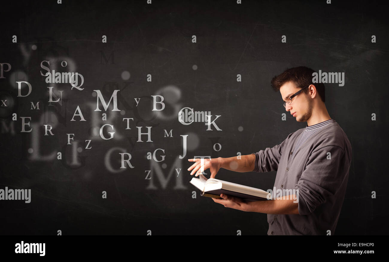 Young man reading a book with alphabet letters Stock Photo - Alamy