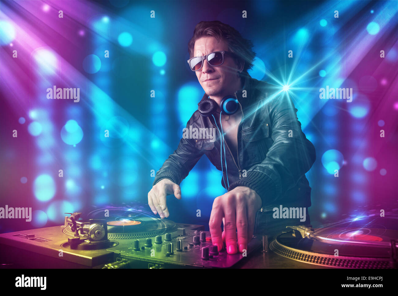 Dj mixing music in a club with blue and purple lights Stock Photo - Alamy