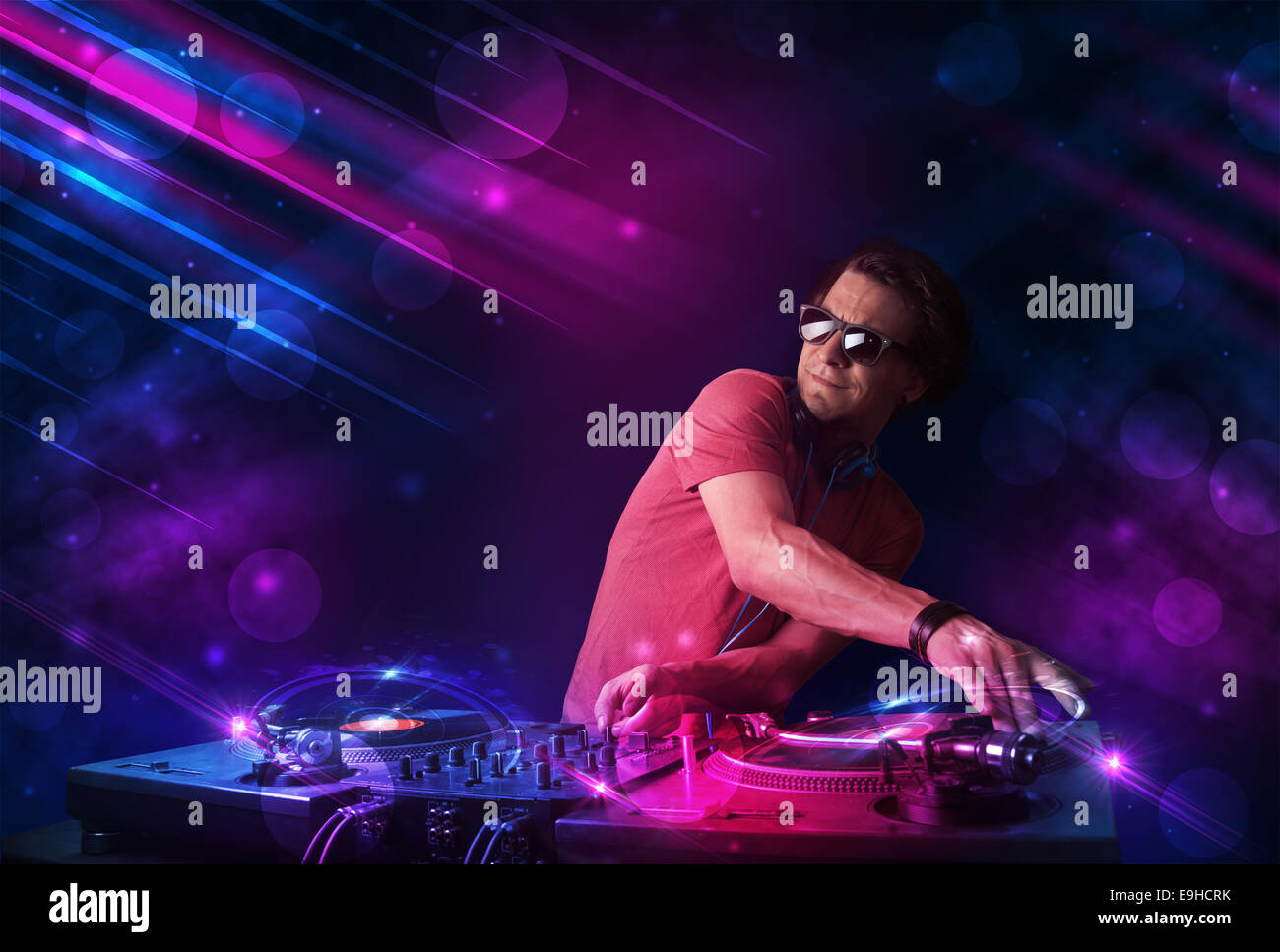 Young DJ playing on turntables with color light effects Stock Photo - Alamy