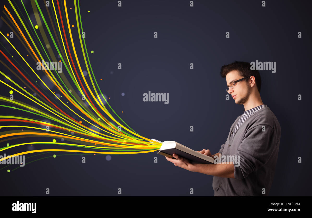 Handsome man reading a book while colorful lines are coming out of the ...