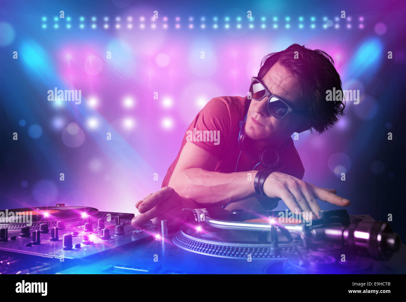 Disc jockey mixing music on turntables on stage with lights and ...
