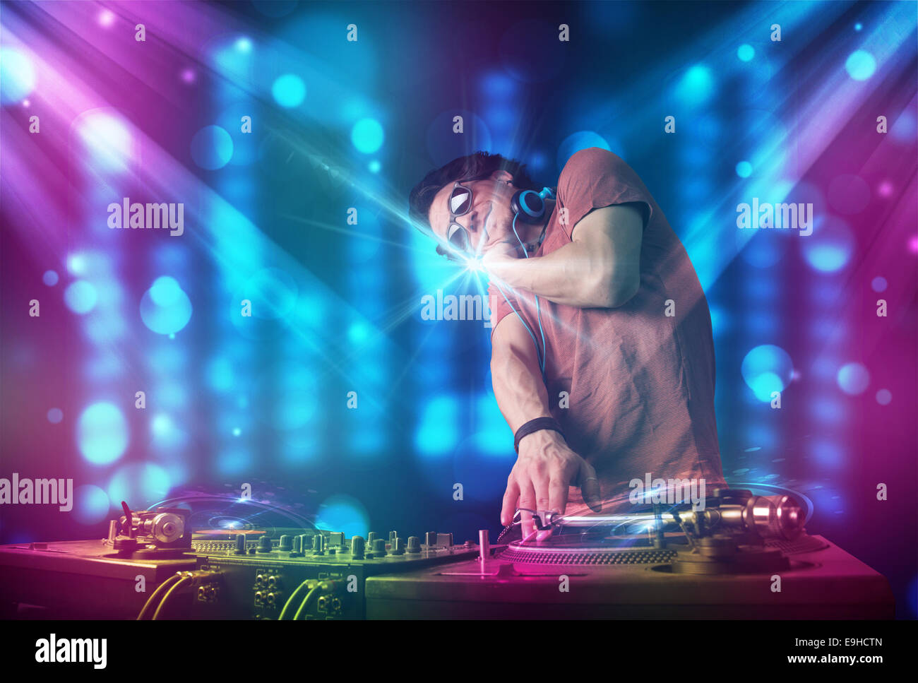 Dj mixing music in a club with blue and purple lights Stock Photo - Alamy