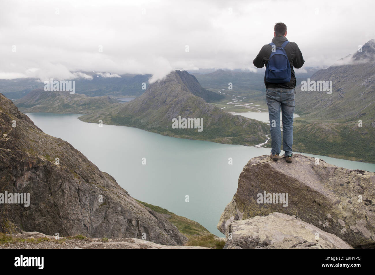 Young man standing on the edge of Besseggen mountain ridge overlooking ...