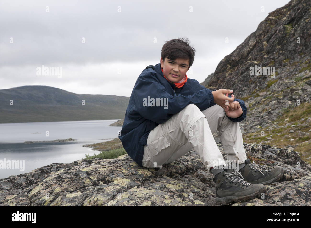 Teenage boy having a rest by Bessvatnet lake during a hike along ...