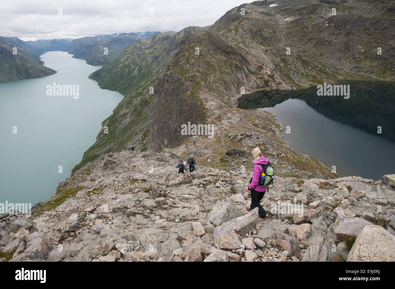 Hikers ascending the western ridge of Besseggen mountain with view over ...