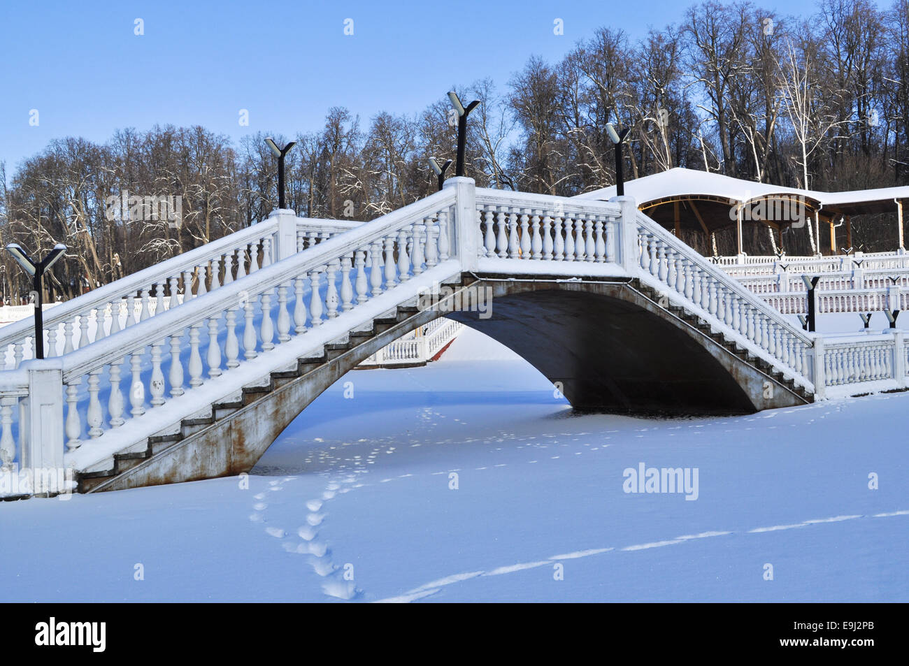 Snow-covered bridge railings through the frozen pond Sunny winter day ...