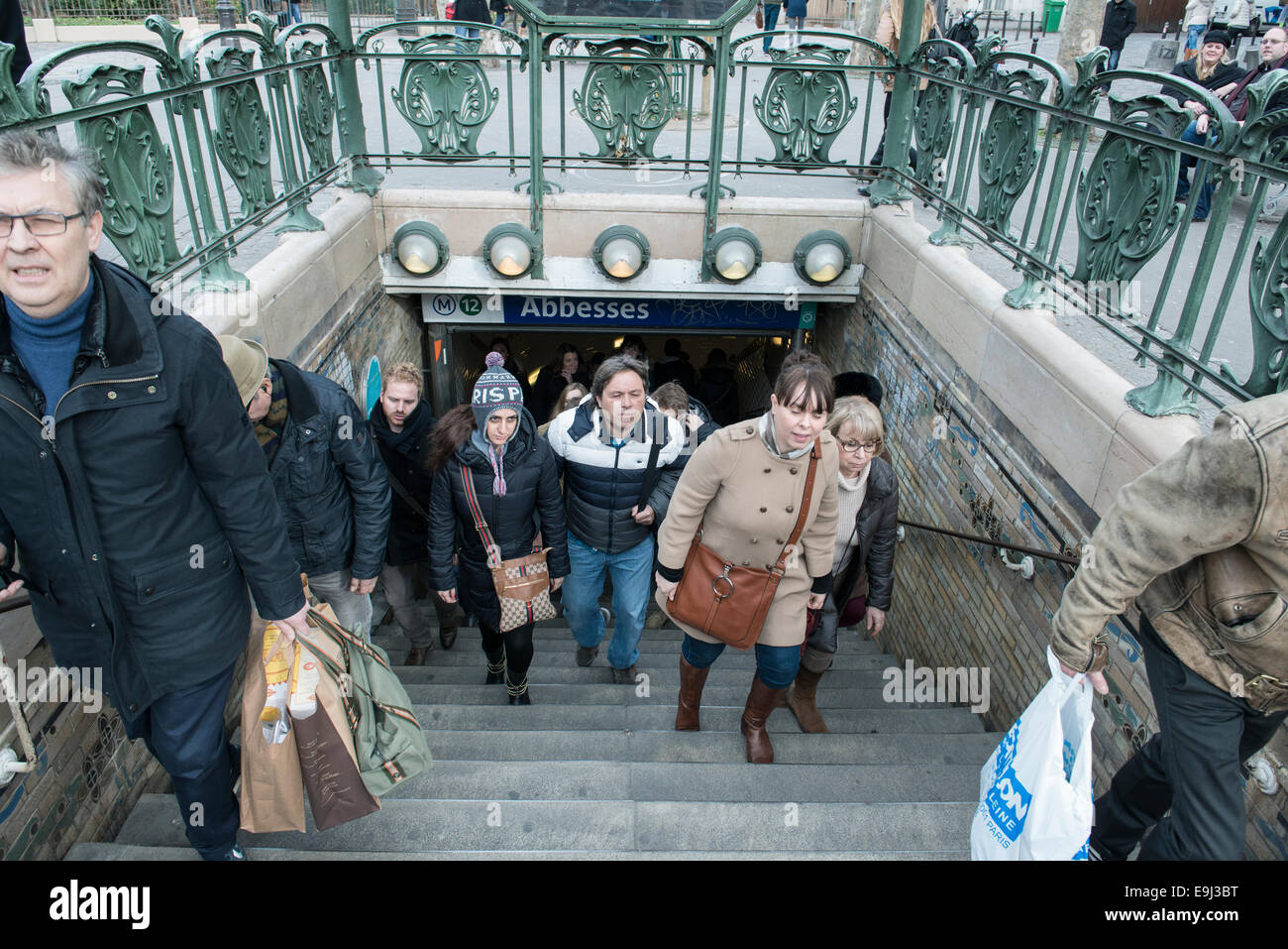 tourists and commuters exit a paris metro train station in winter with ...