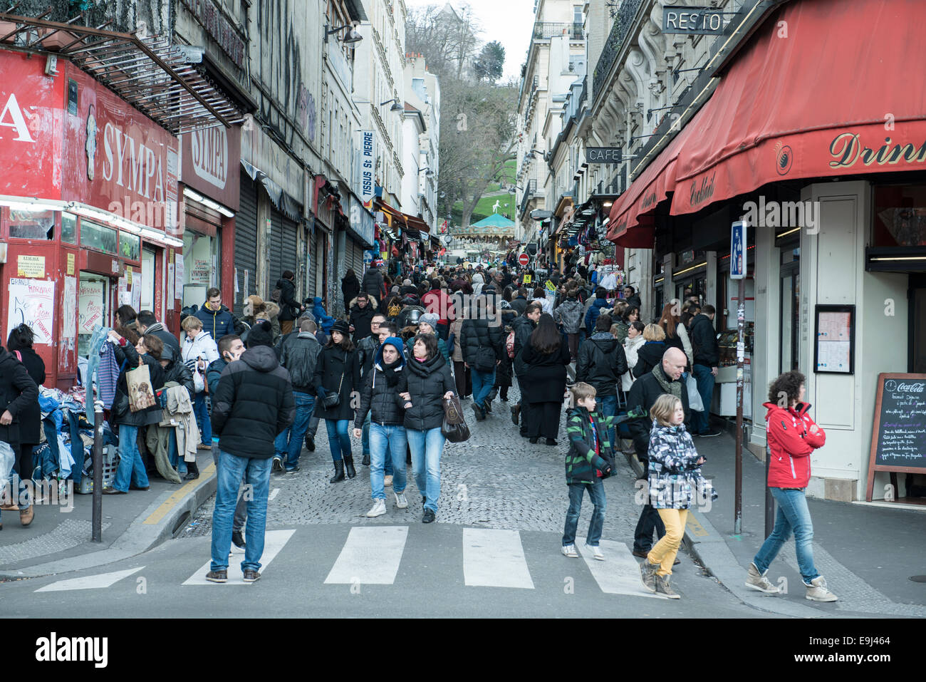 a crowd of people walking on a pedestrianised street going up hill in ...