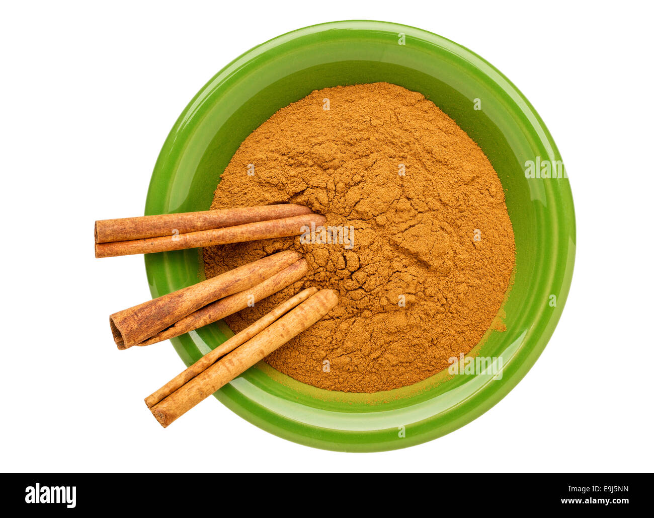 cinnamon (cassia) bark powder and sticks on an isolated green ceramic ...
