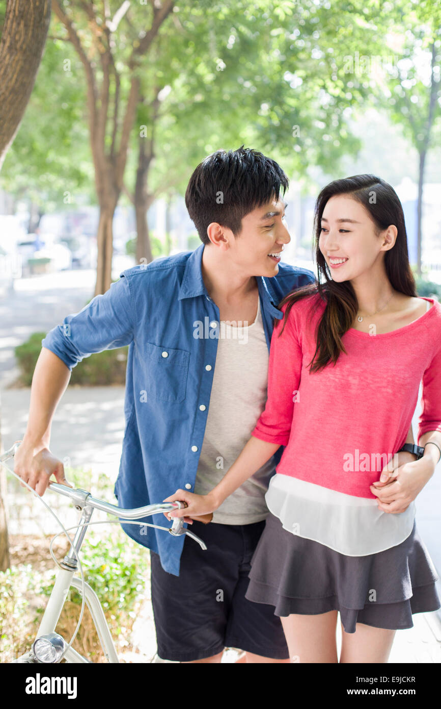 Young couple pushing bicycle at campus Stock Photo - Alamy