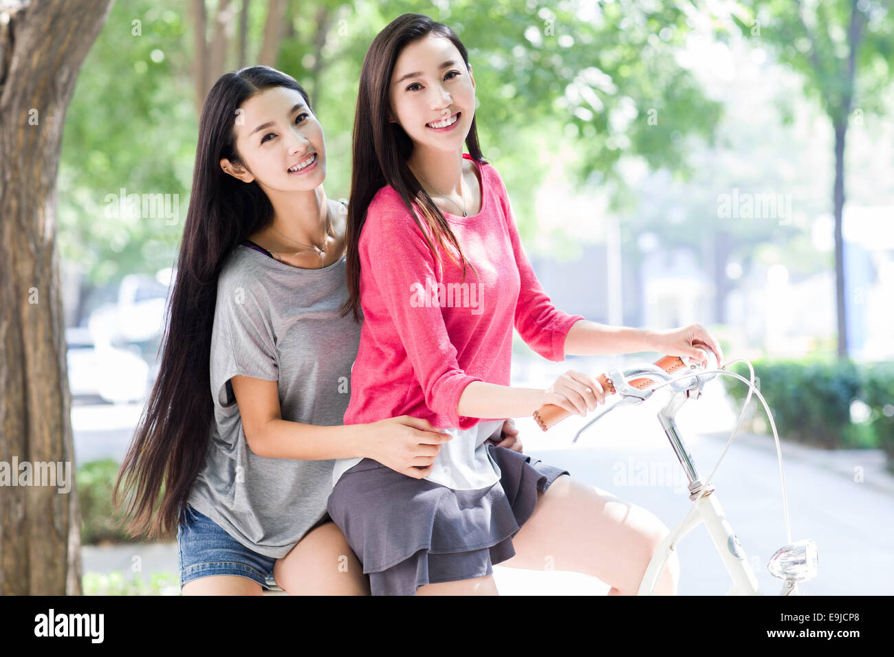 Best female friends riding bicycle at campus Stock Photo - Alamy