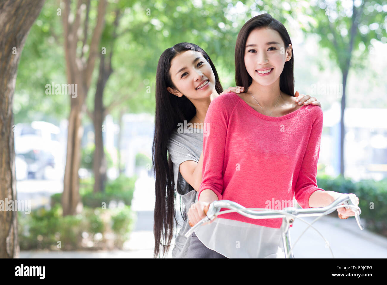 Best female friends riding bicycle at campus Stock Photo - Alamy